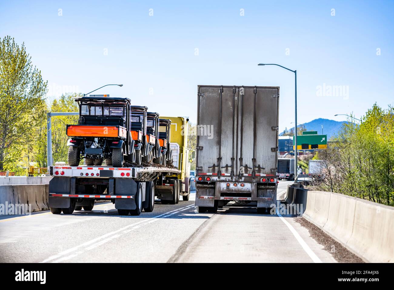 Two heavy-duty loaded industrial big rigs semi trucks with flat bed and ...