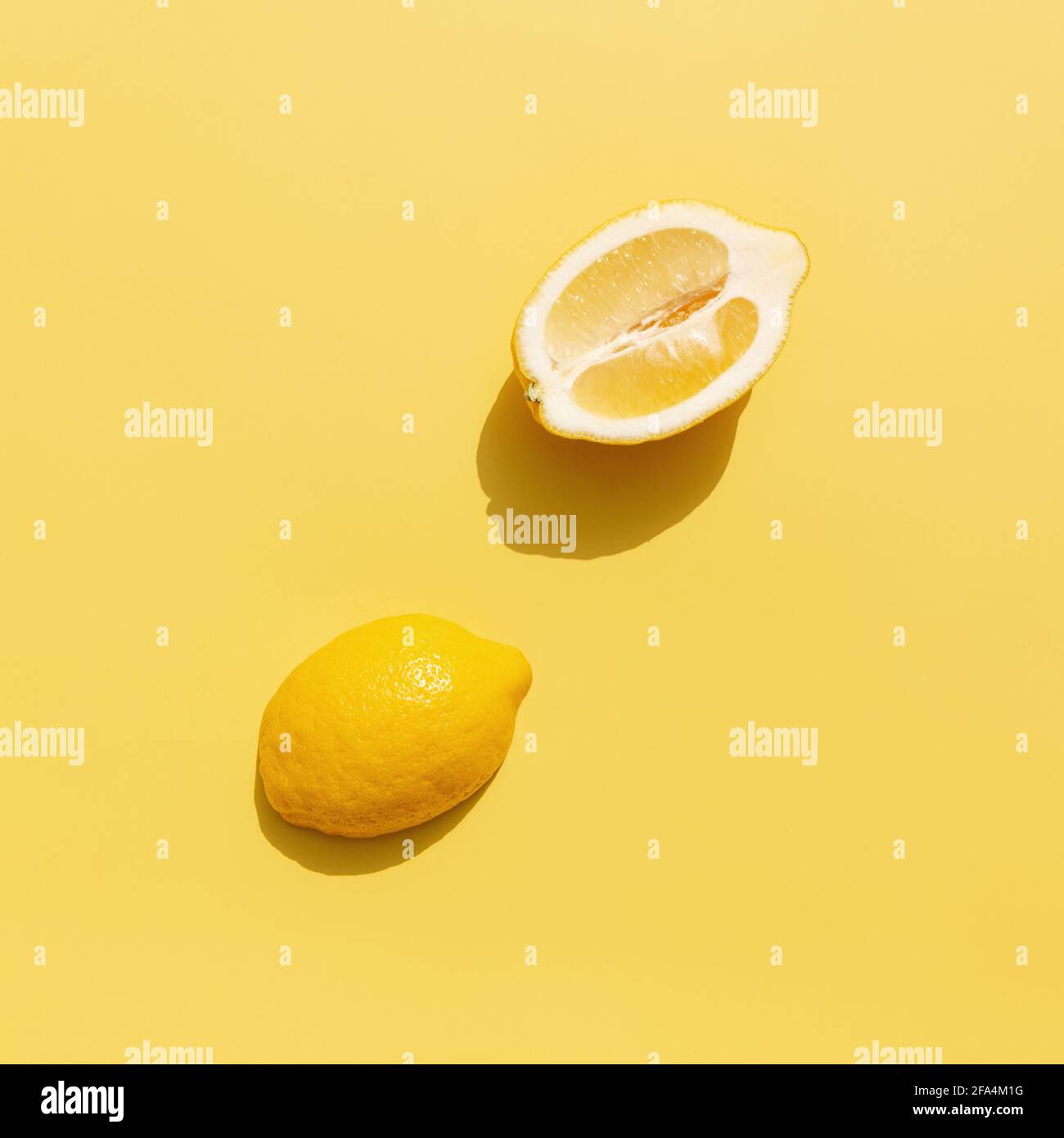 Two halved cuts of lemon with shadow on yellow background. Healthy ...