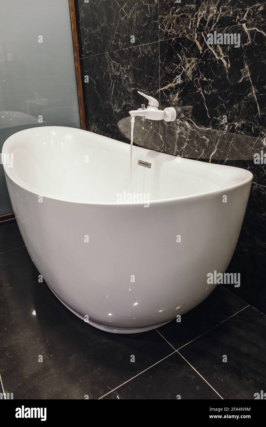 Vertical shot of a freestanding acrylic bathtub inside a luxurious ...