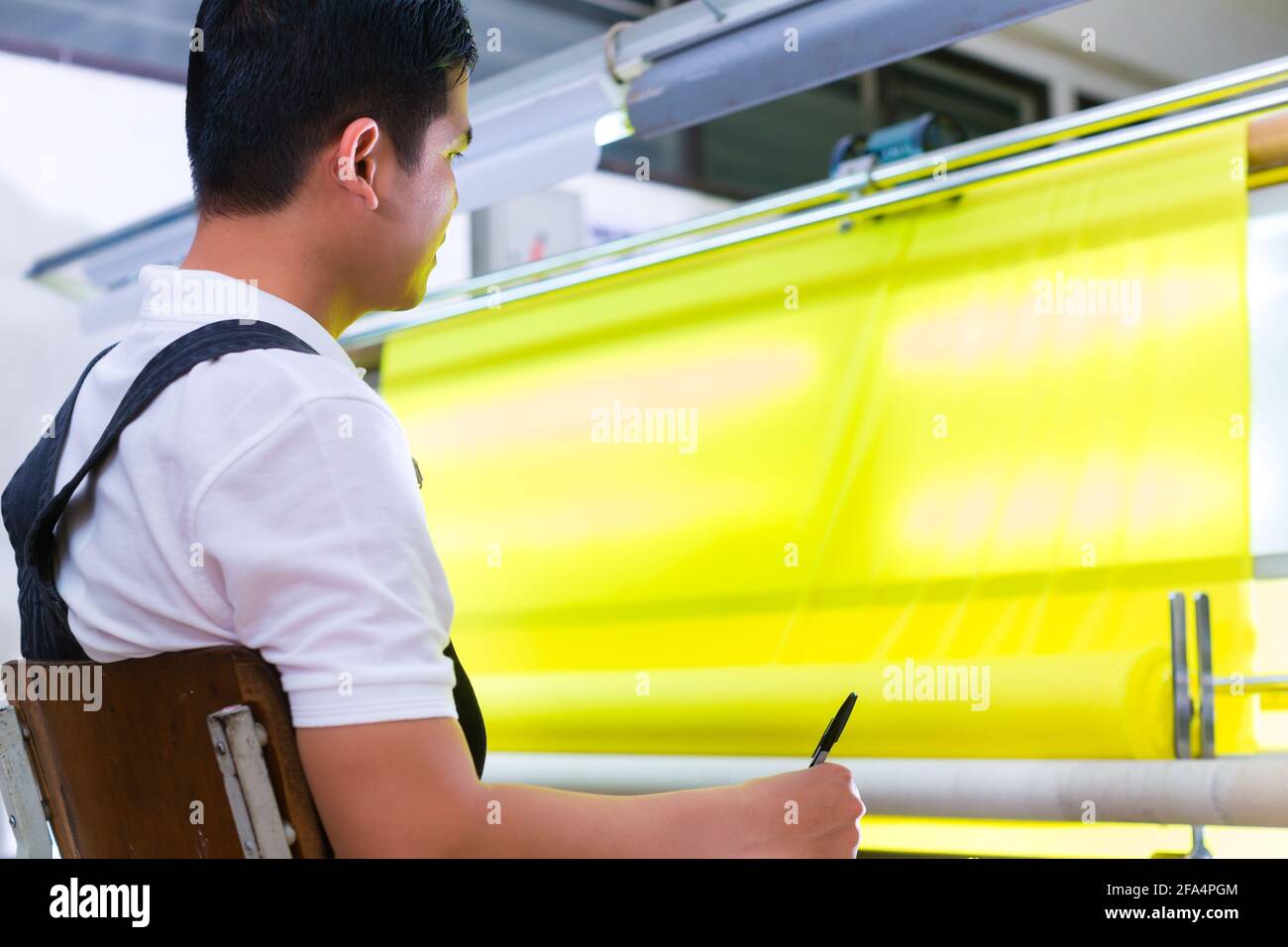 Indonesian textile worker controls the quality of a fabric roll in ...