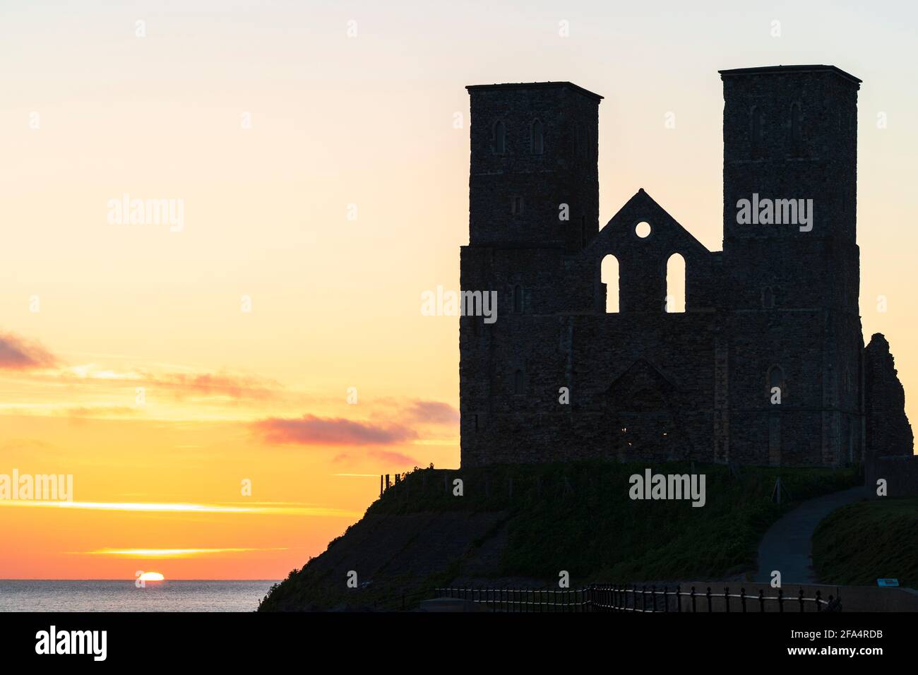 Sunrise over the sea on the north Kent Coast with the 12th century twin ...