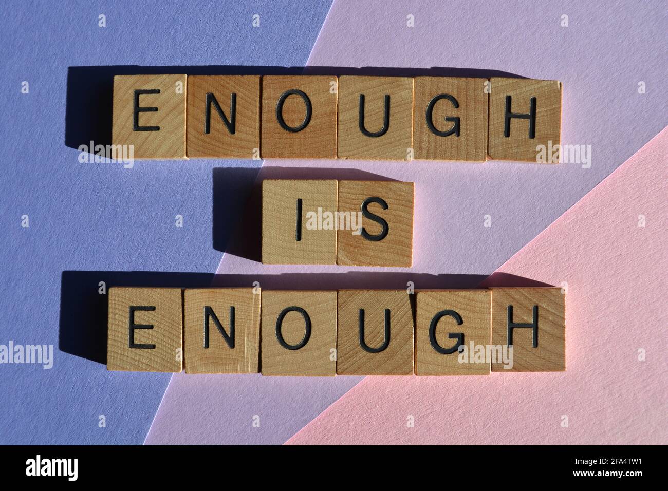 Enough is Enough, phrase in wooden alphabet letters isolated on pink ...
