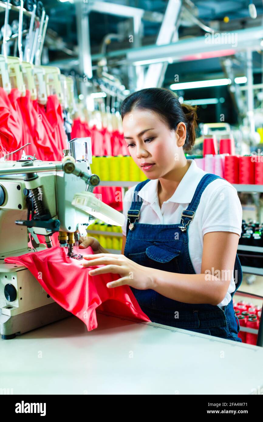 Seamstress or worker in factory sewing with industrial machine, she is ...