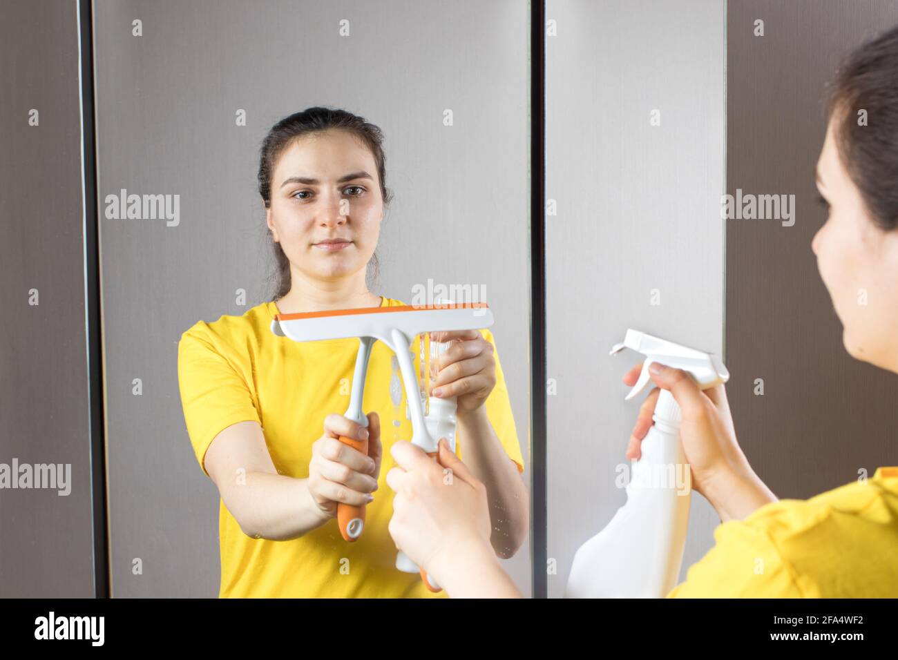 The cleaning lady cleans the mirror with a water dispenser and window ...