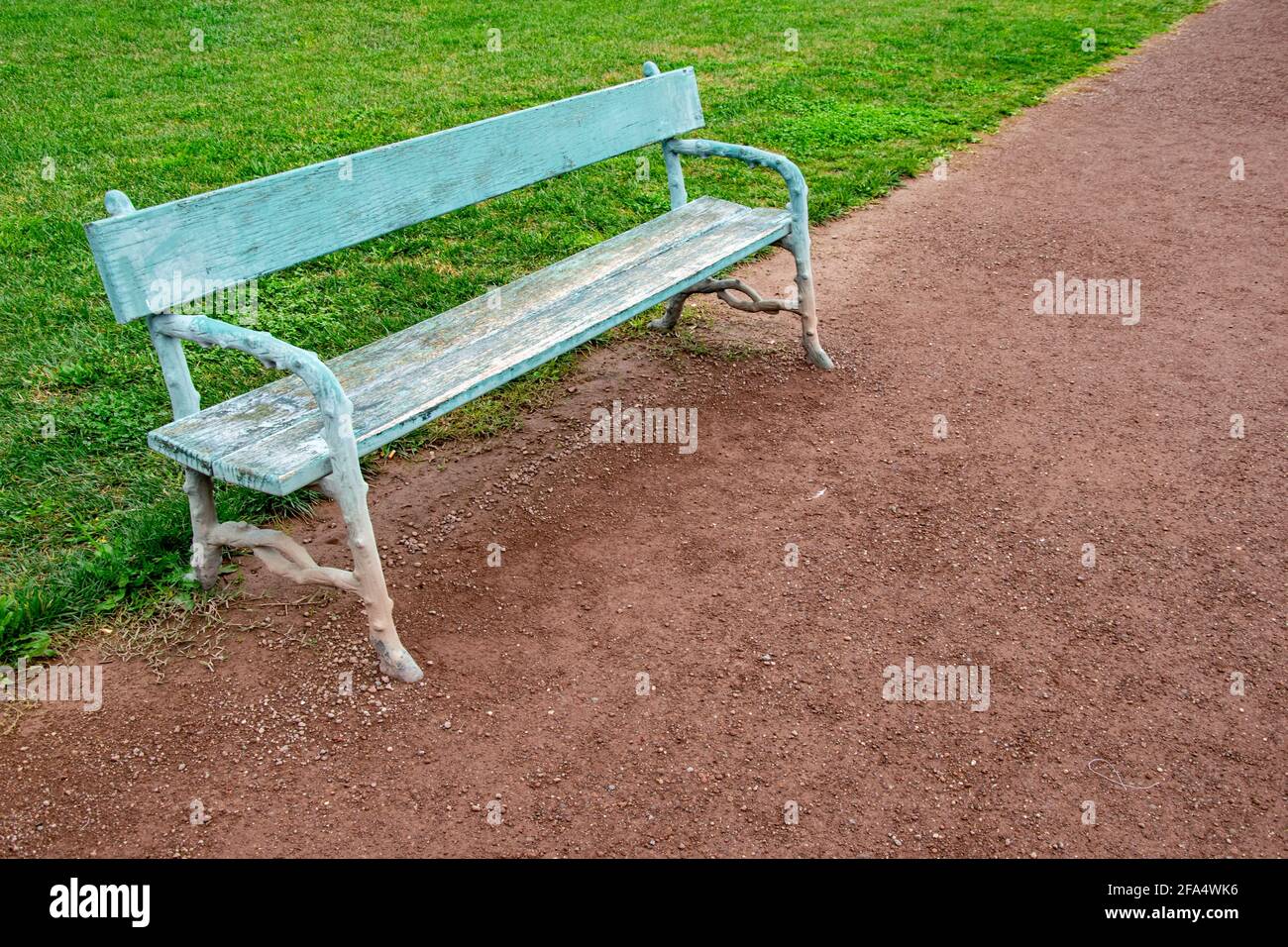 a single turquoise coloured wooden bench along a gravel path in Rome ...