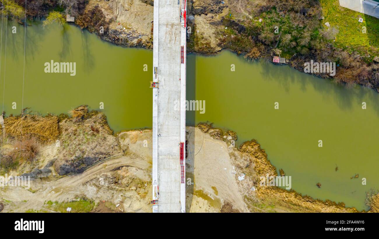 Above top view, overhead, on unfinished bridge, road over river is ...