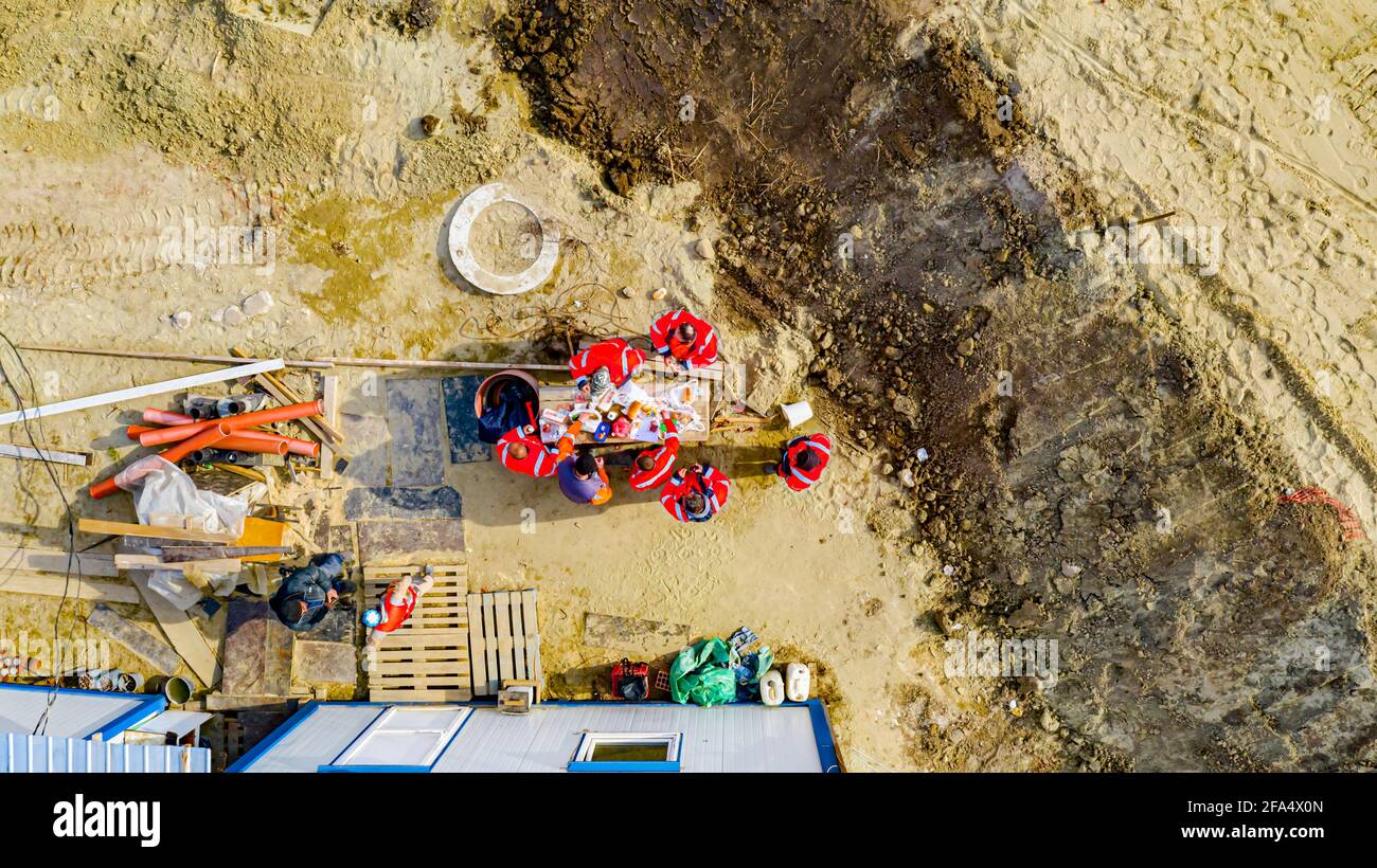 Construction workers are on pause for meal, they are eating as standing ...