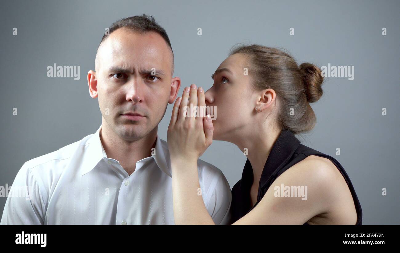 Photo of girl talking secret on grey background Stock Photo - Alamy