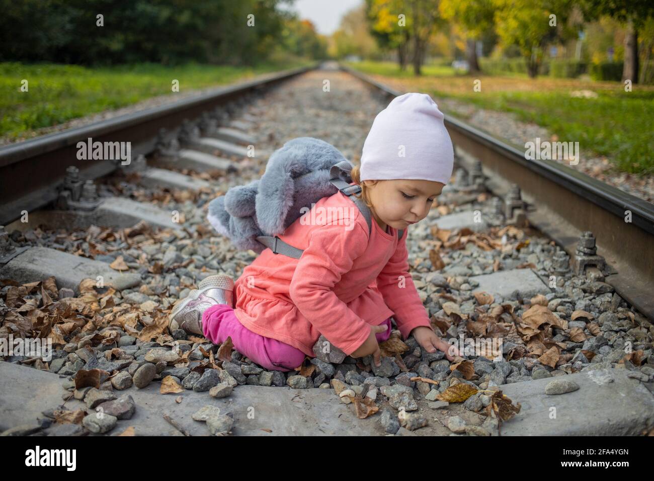 little girl sitting on the railroad tracks. toddler plays on railroad ...