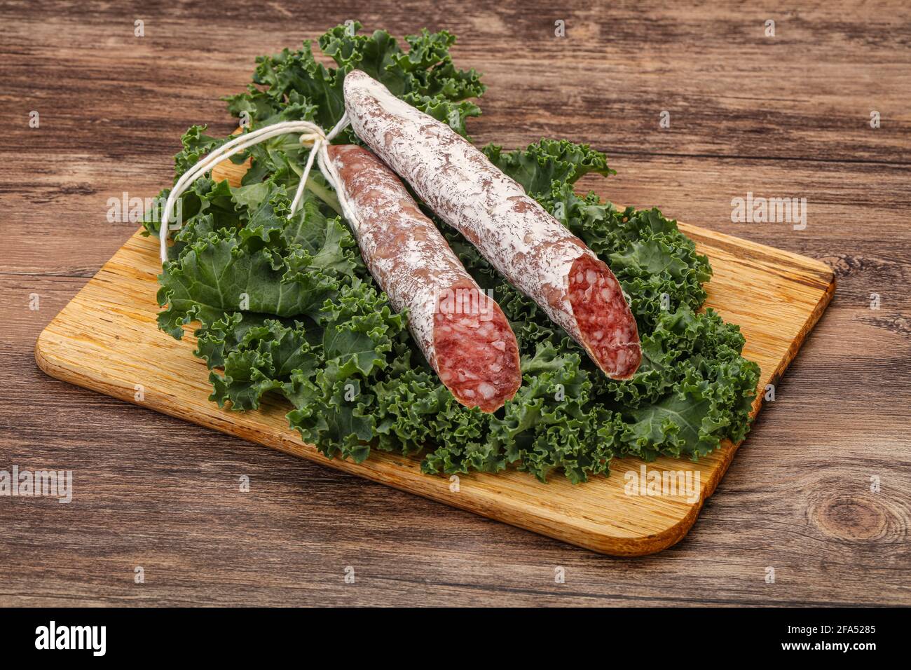 Spanish Fuet sausage with salad leaves over wooden background Stock ...