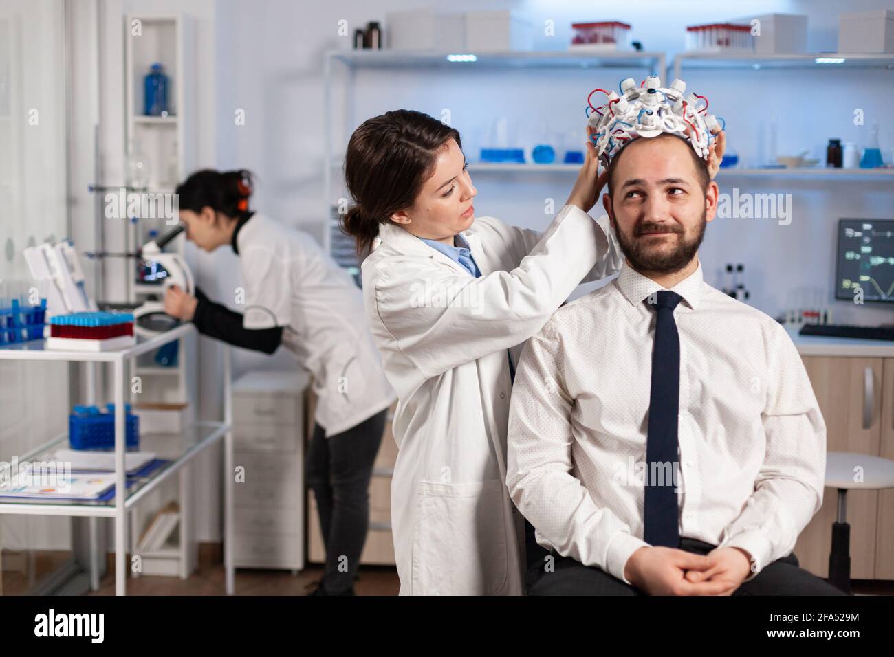 Woman researcher putting brainwave scanning headset to patient ...