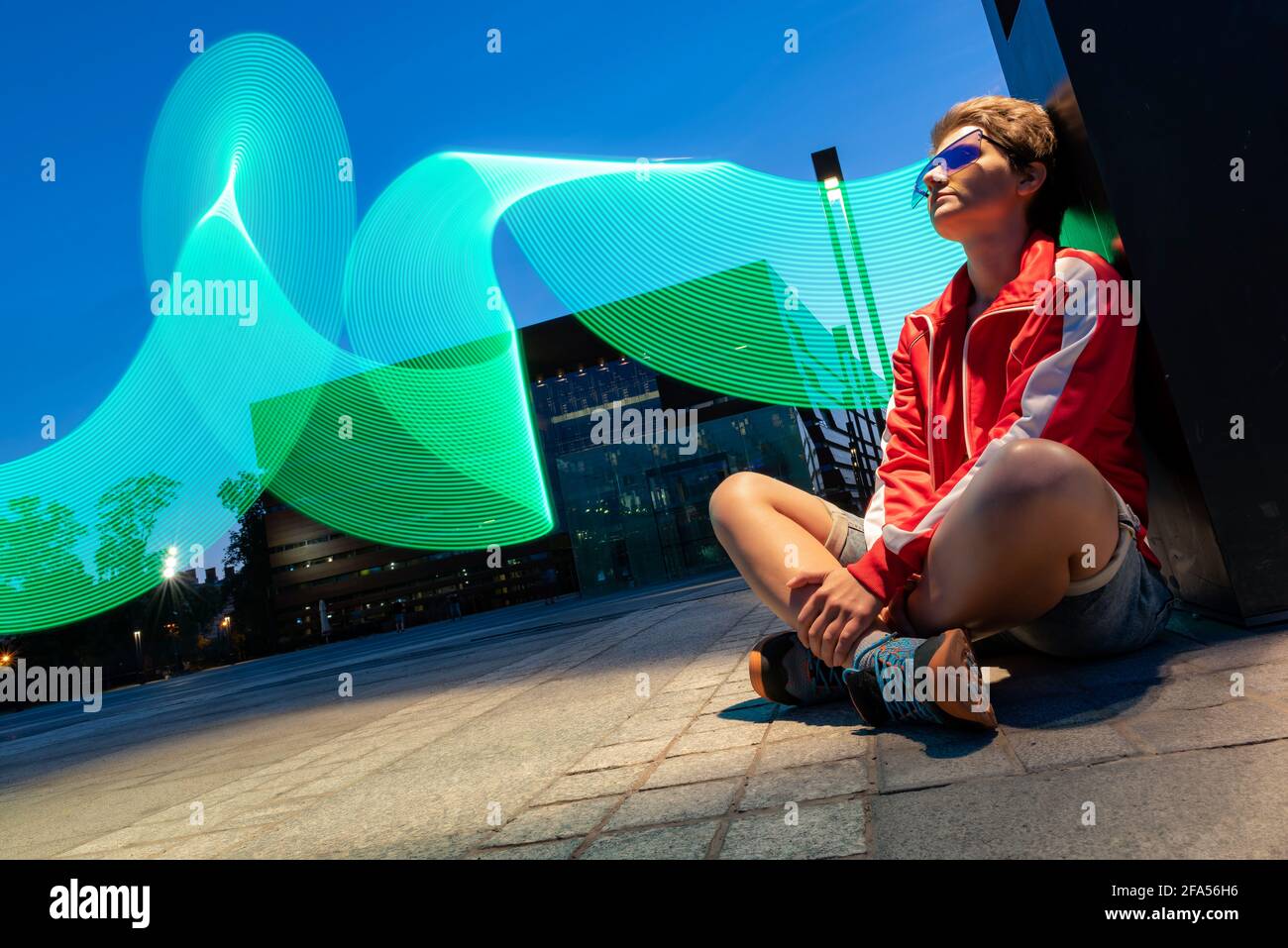 portrait of young woman sitting outdoor on a ground on a long exposure ...