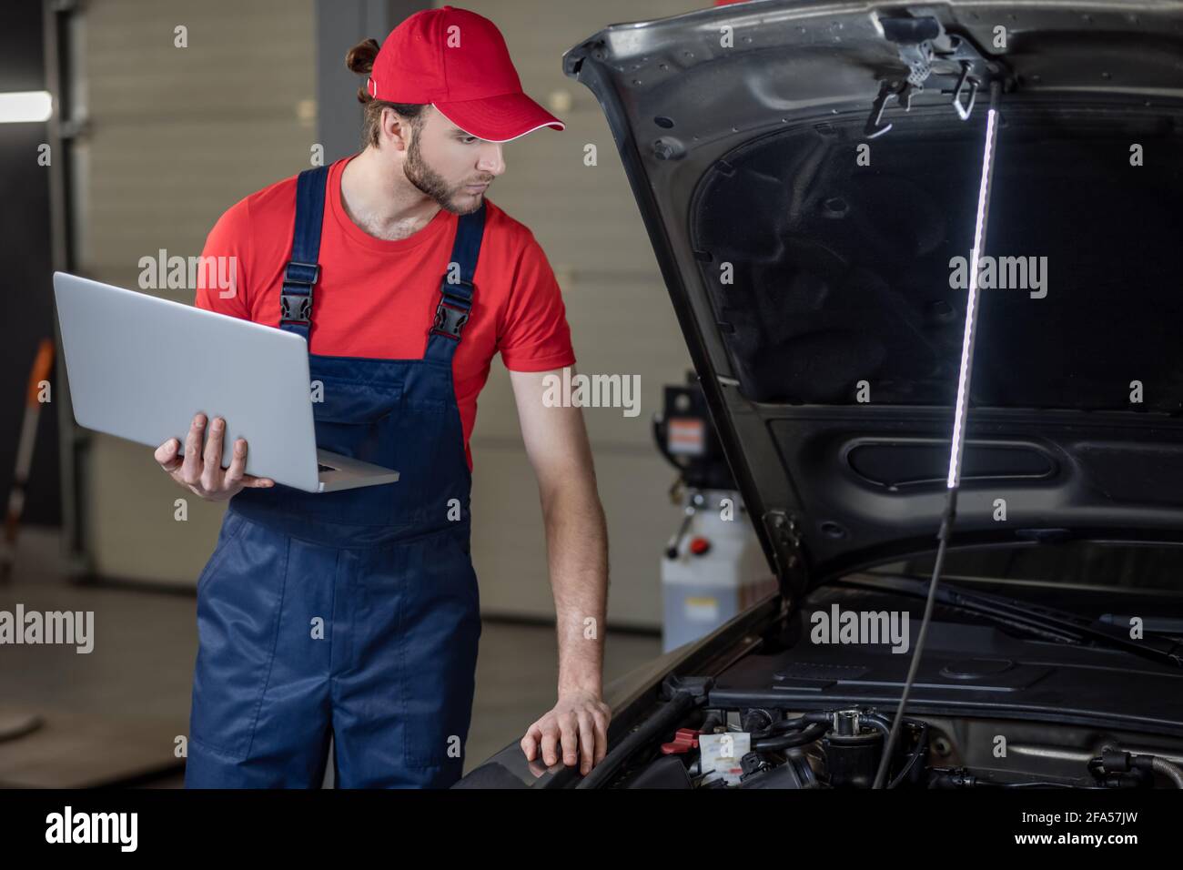 Man with laptop checking car anatomy Stock Photo - Alamy