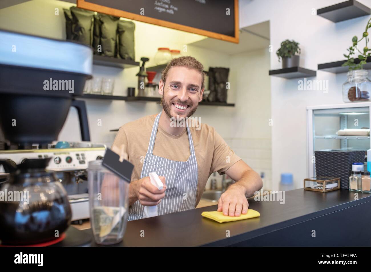 Happy man with napkin and disinfectant behind bar Stock Photo - Alamy