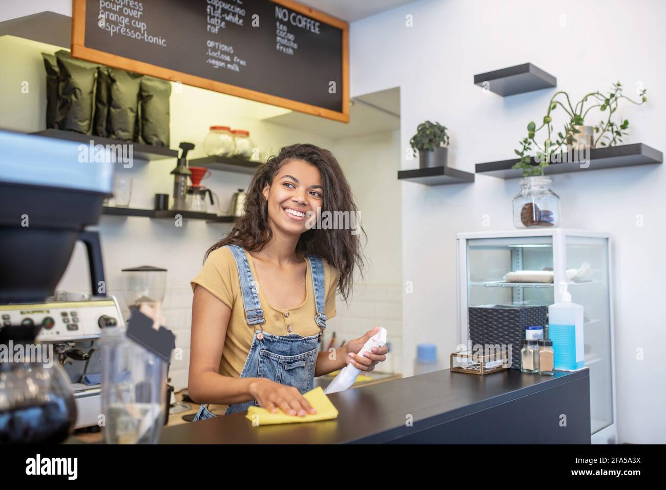 Young joyful brown woman wiping bar counter Stock Photo - Alamy