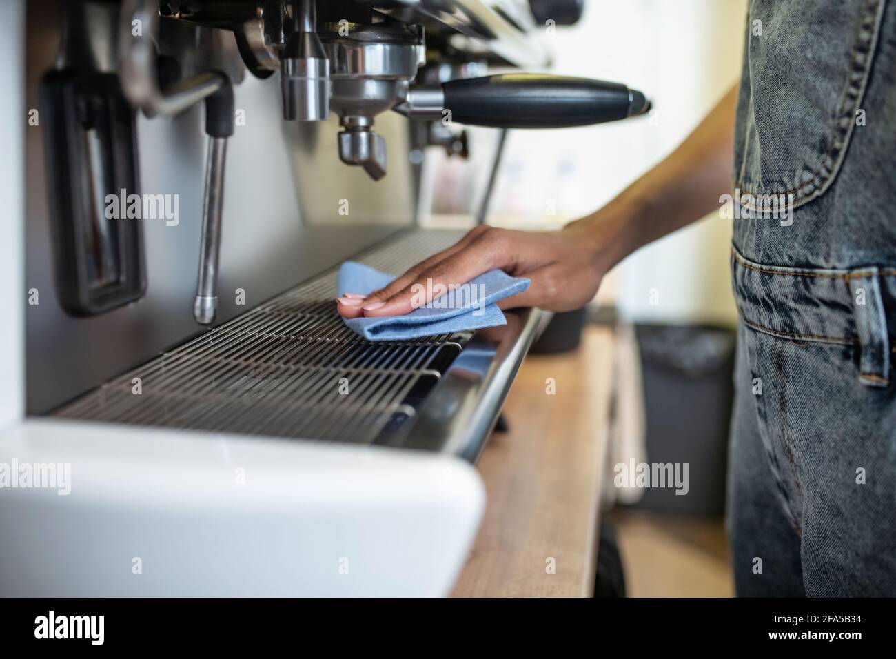 Womans hand washing surface of coffee machine Stock Photo - Alamy