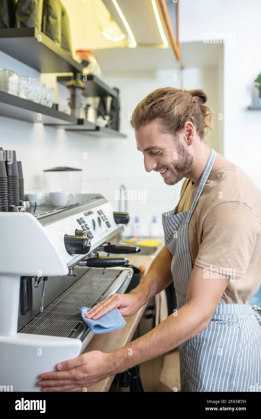Smiling man wiping surface of coffee machine Stock Photo - Alamy