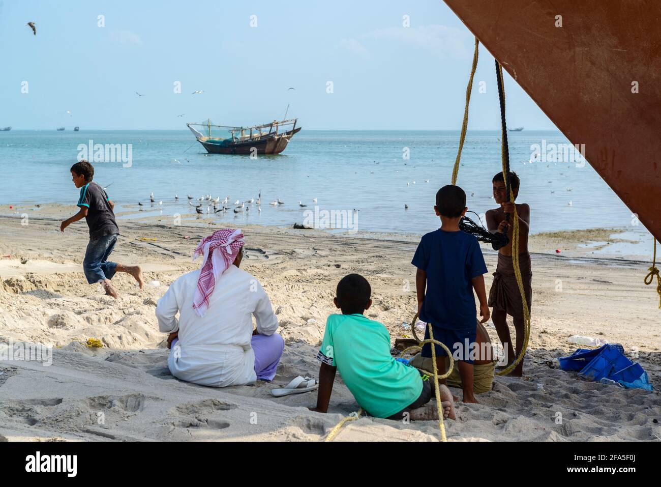 Fishing activities on the beach of Shannah, Oman. Man and boys sitting ...