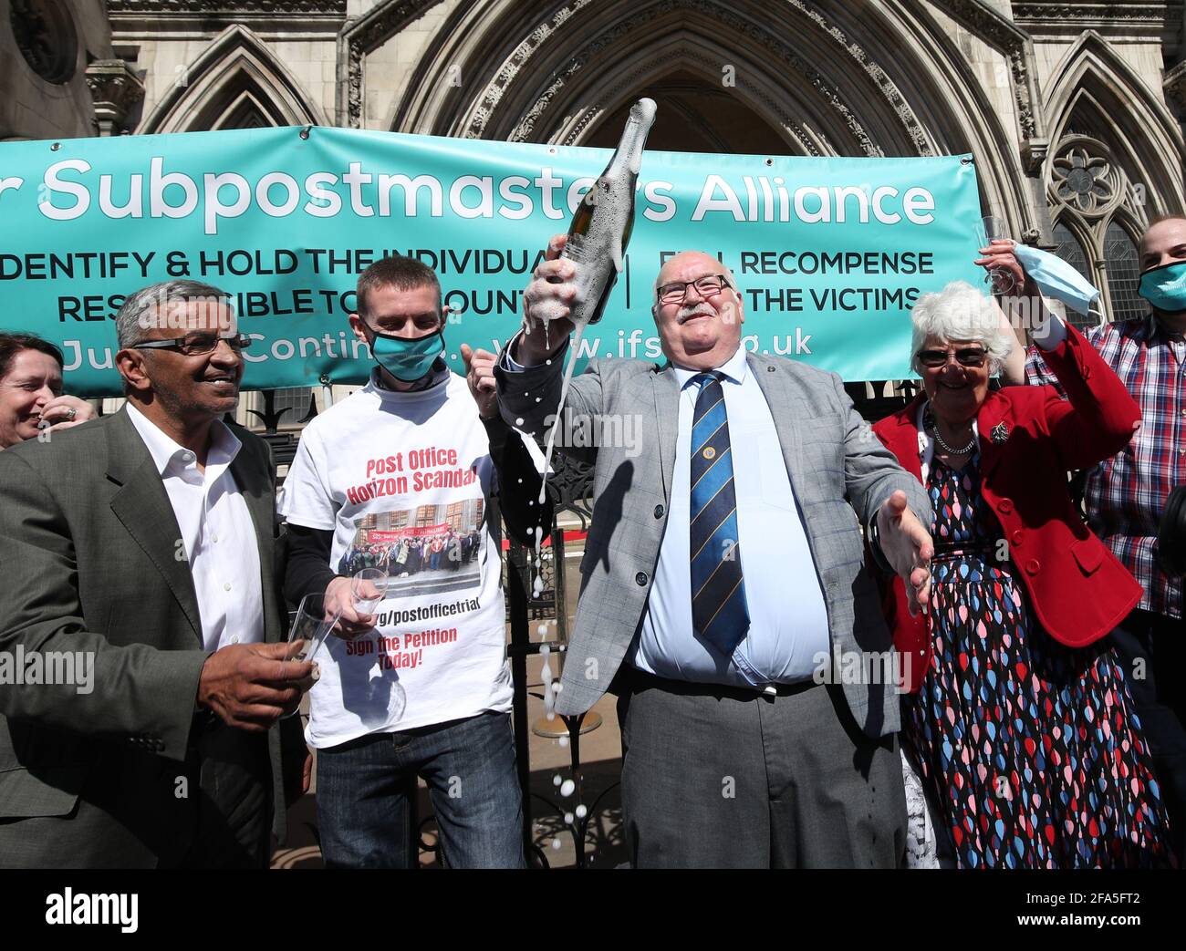 Former post office worker Tom Hedges (centre) pops a bottle champagne ...