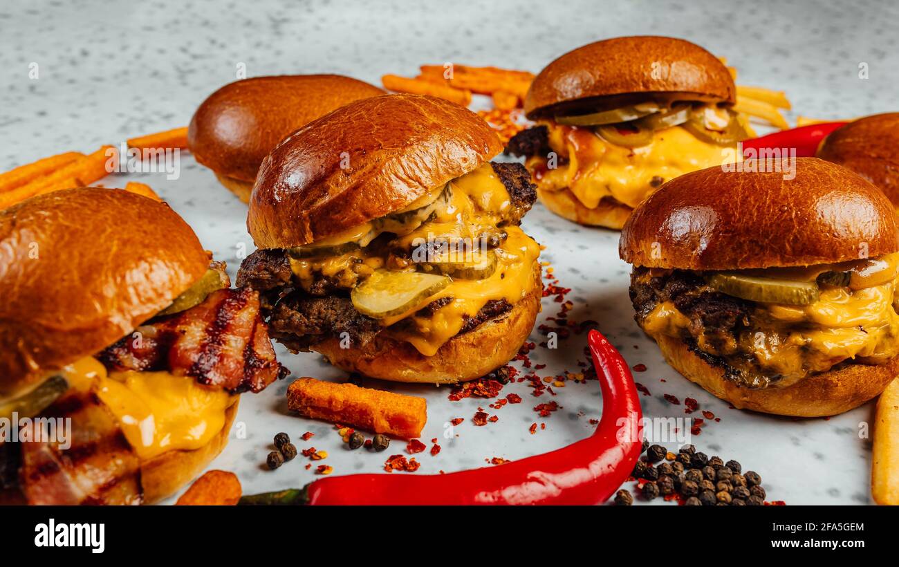 Closeup shot of tasty smash burgers, French fries, and red spicy pepper ...