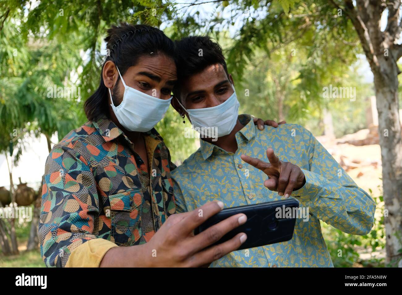 Young Indian male friends in protective medical face masks taking a ...
