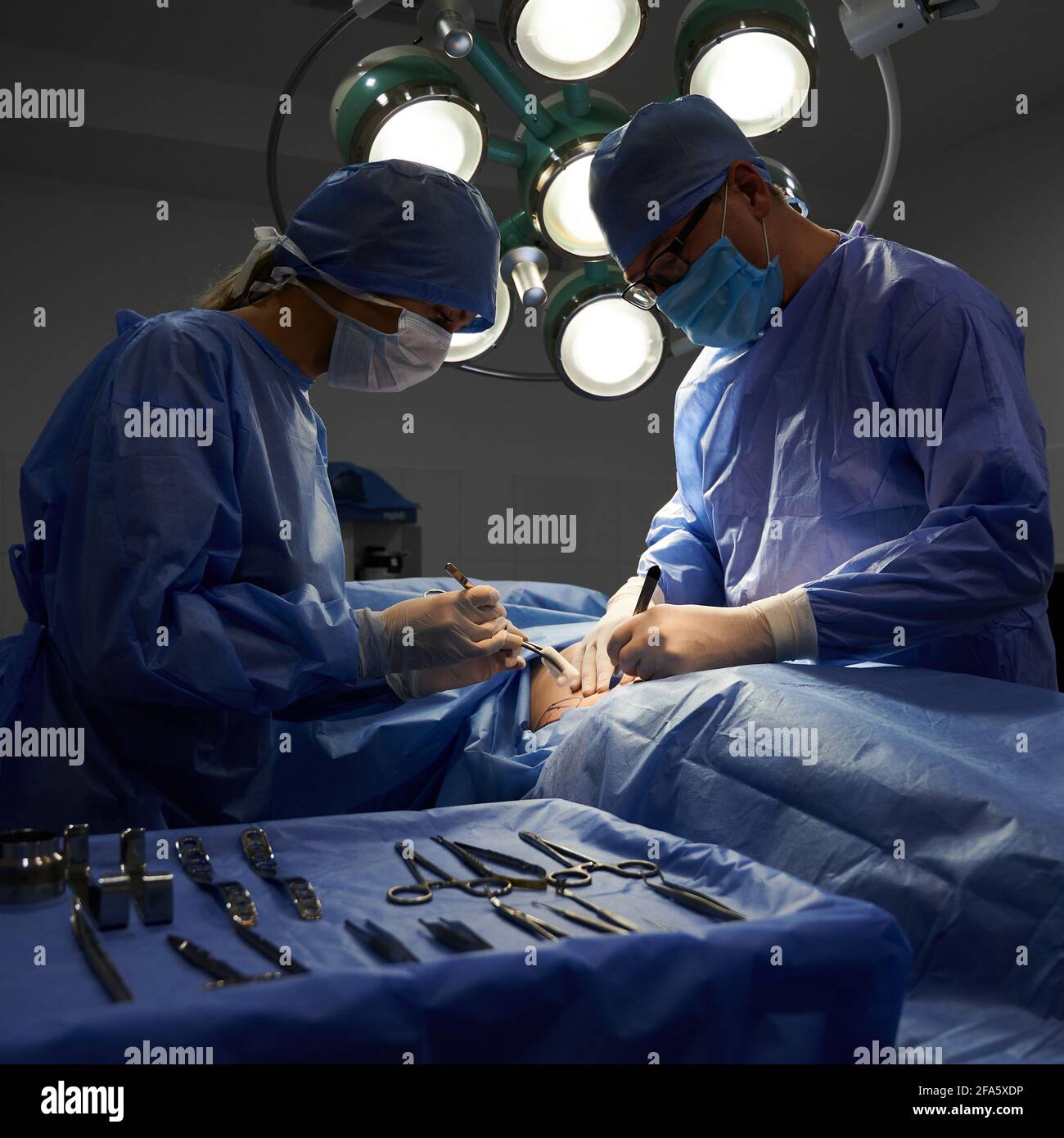 Doctor and assistant performing aesthetic surgery in operating room ...