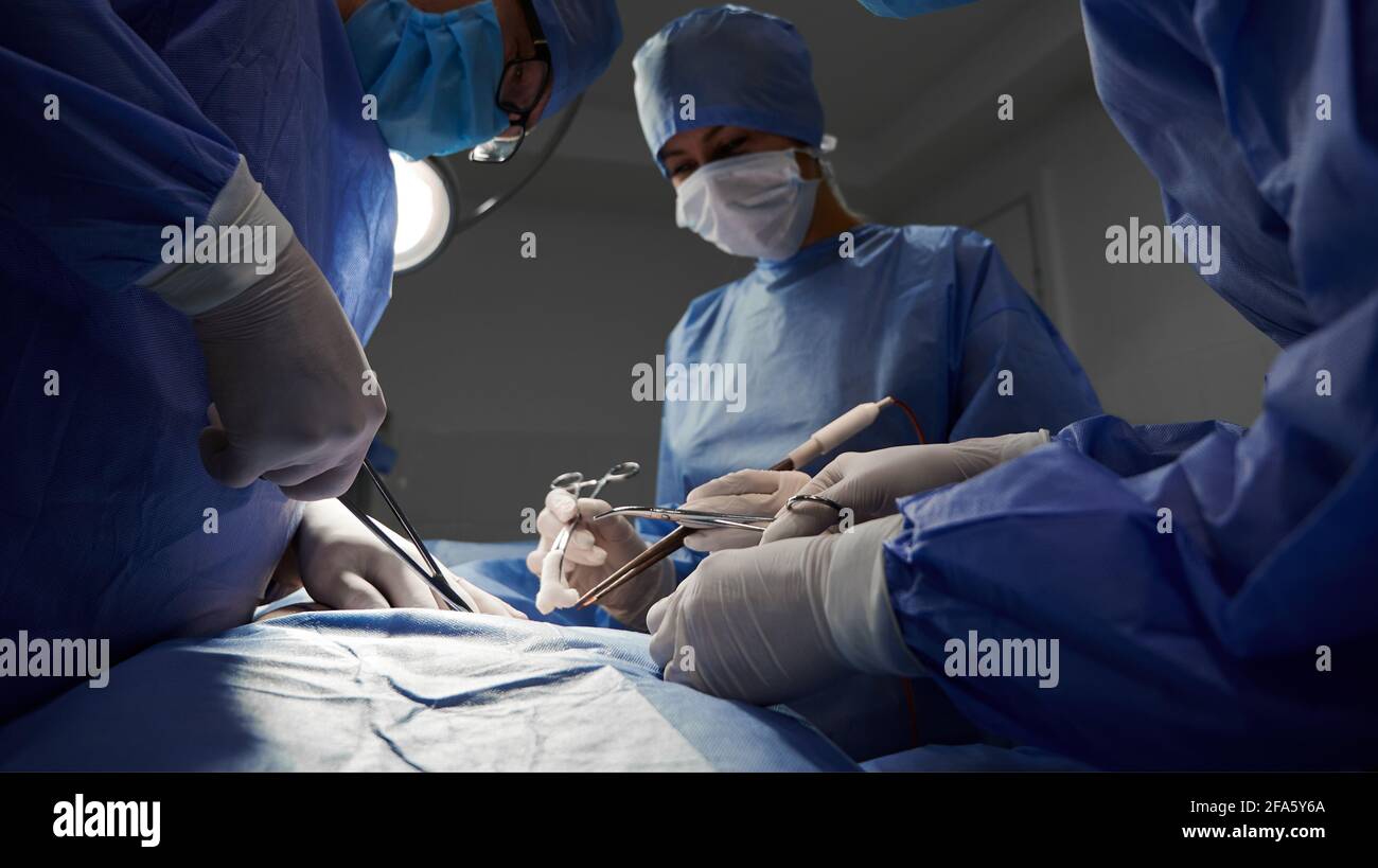 Surgical team in blue medical suits using medical instruments and ...