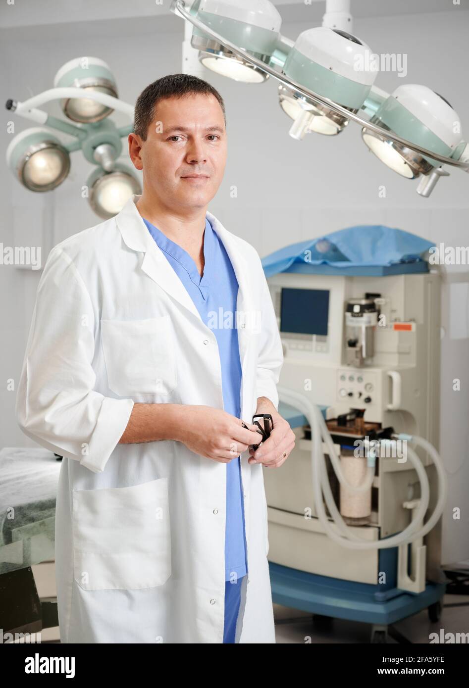 Front view of man surgeon looking at camera, standing in operating room ...