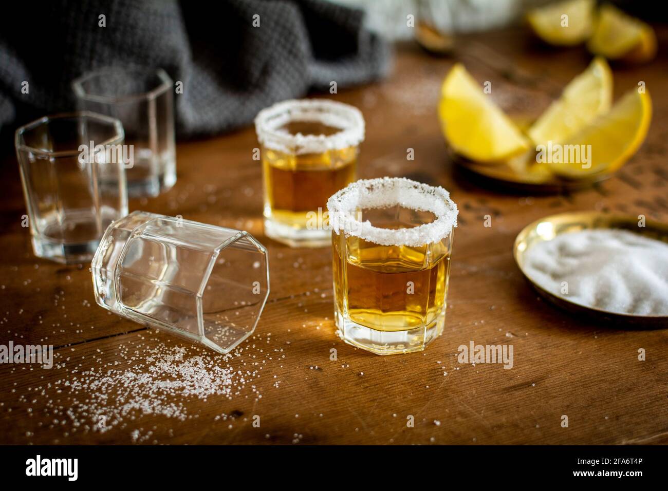 A few shot glasses of tequila shots with a salt brim and lemon slices ...