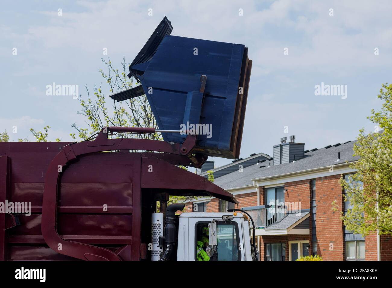 The garbage truck prepares to take in garbage bins inside garbage ...