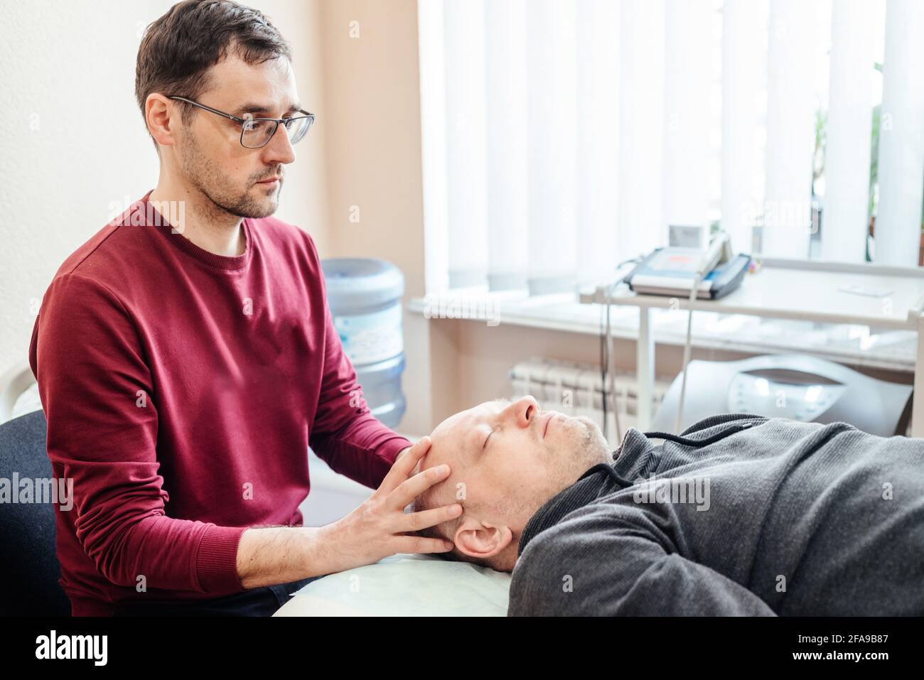 Craniosacral therapy practitioner giving a male patient CST ostheopatic ...
