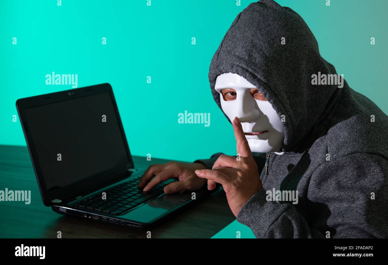 Thief hacker in mask stealing personal information from laptop. Concept ...