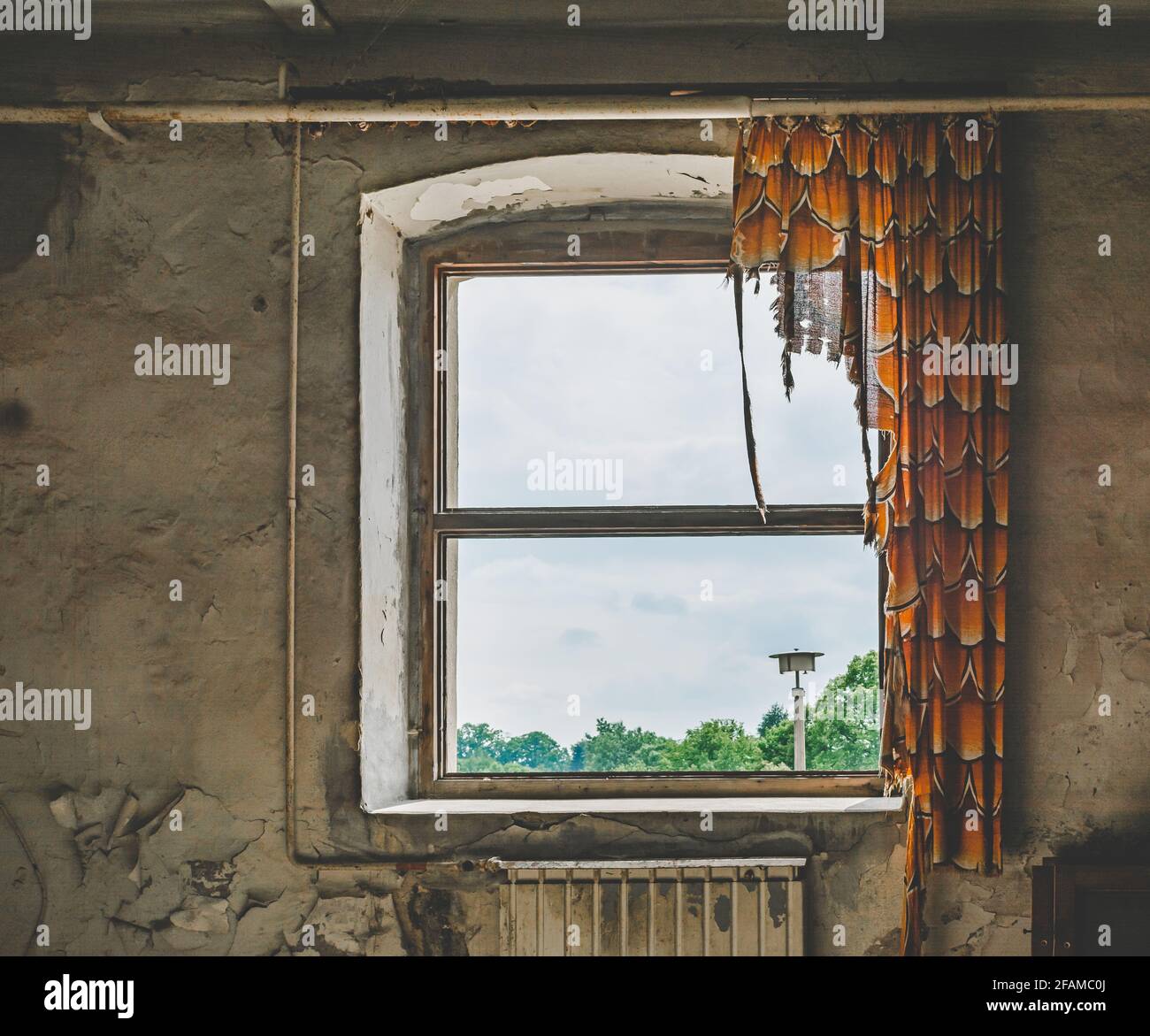 Weathered building with damaged curtain hanging on the aged window ...