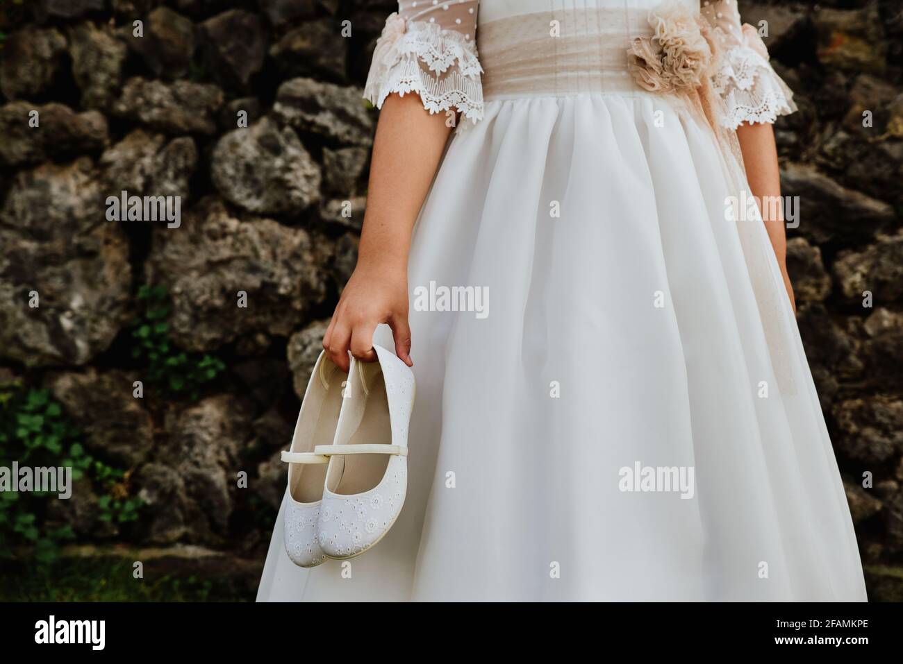 Communion girl with white dress holding white shoes Stock Photo - Alamy