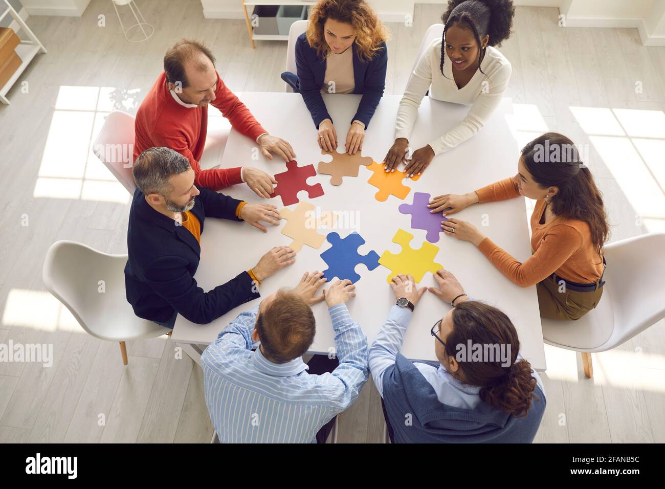 Diverse business team sitting around office table and trying to fit ...