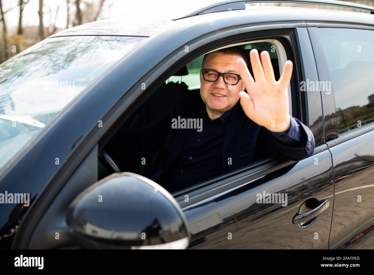 mature man driving car is happy and shows his satisfaction by smiling ...