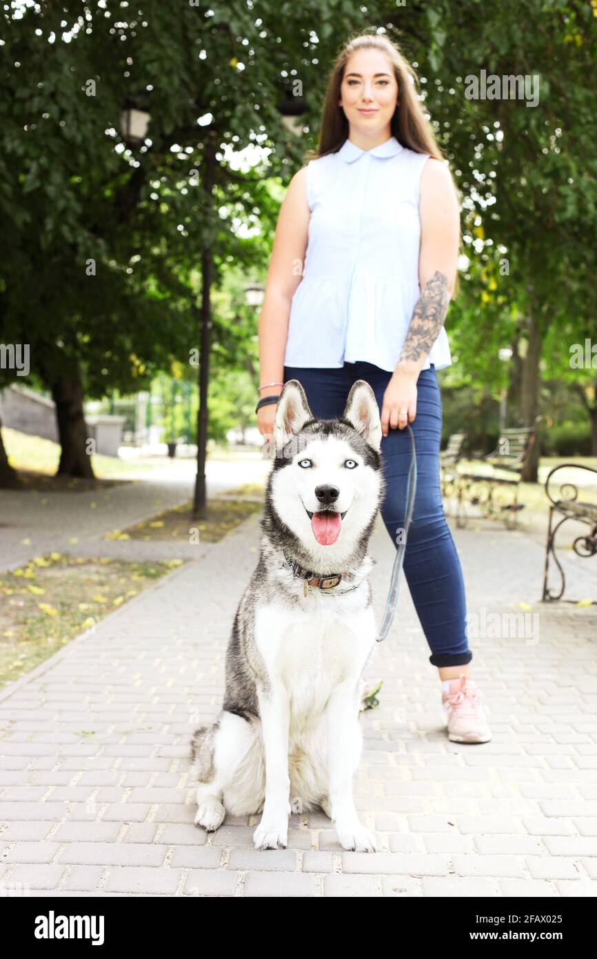 Young beautiful curvy woman walking her cute furry siberian husky dog ...