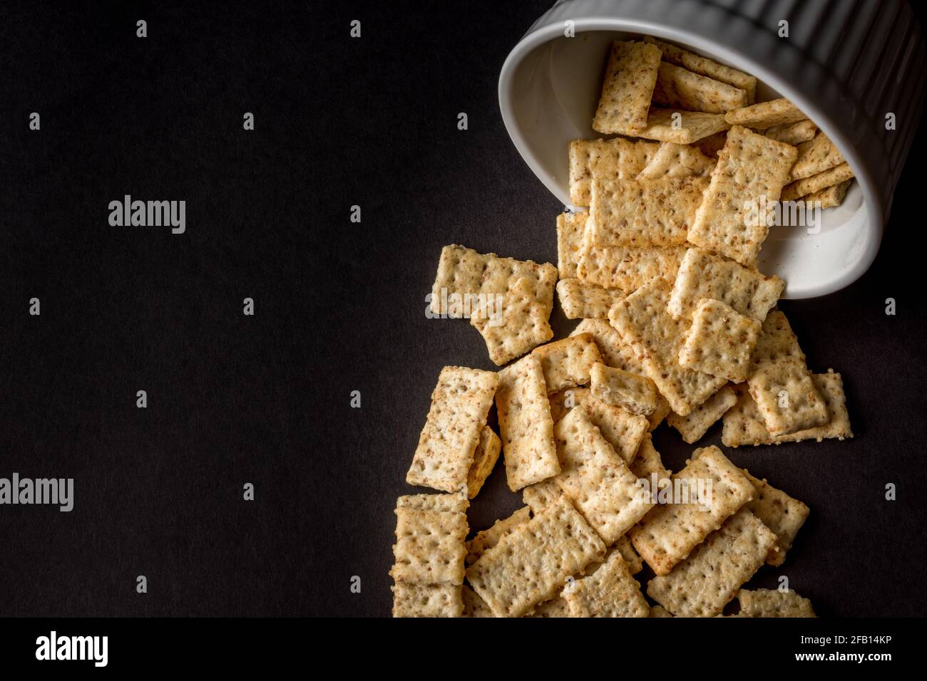 Rectangular crackers poured out from the bowl in black background Stock ...