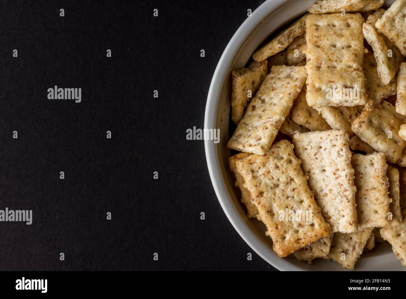 Top view of rectangular crackers in the bowl with black background ...