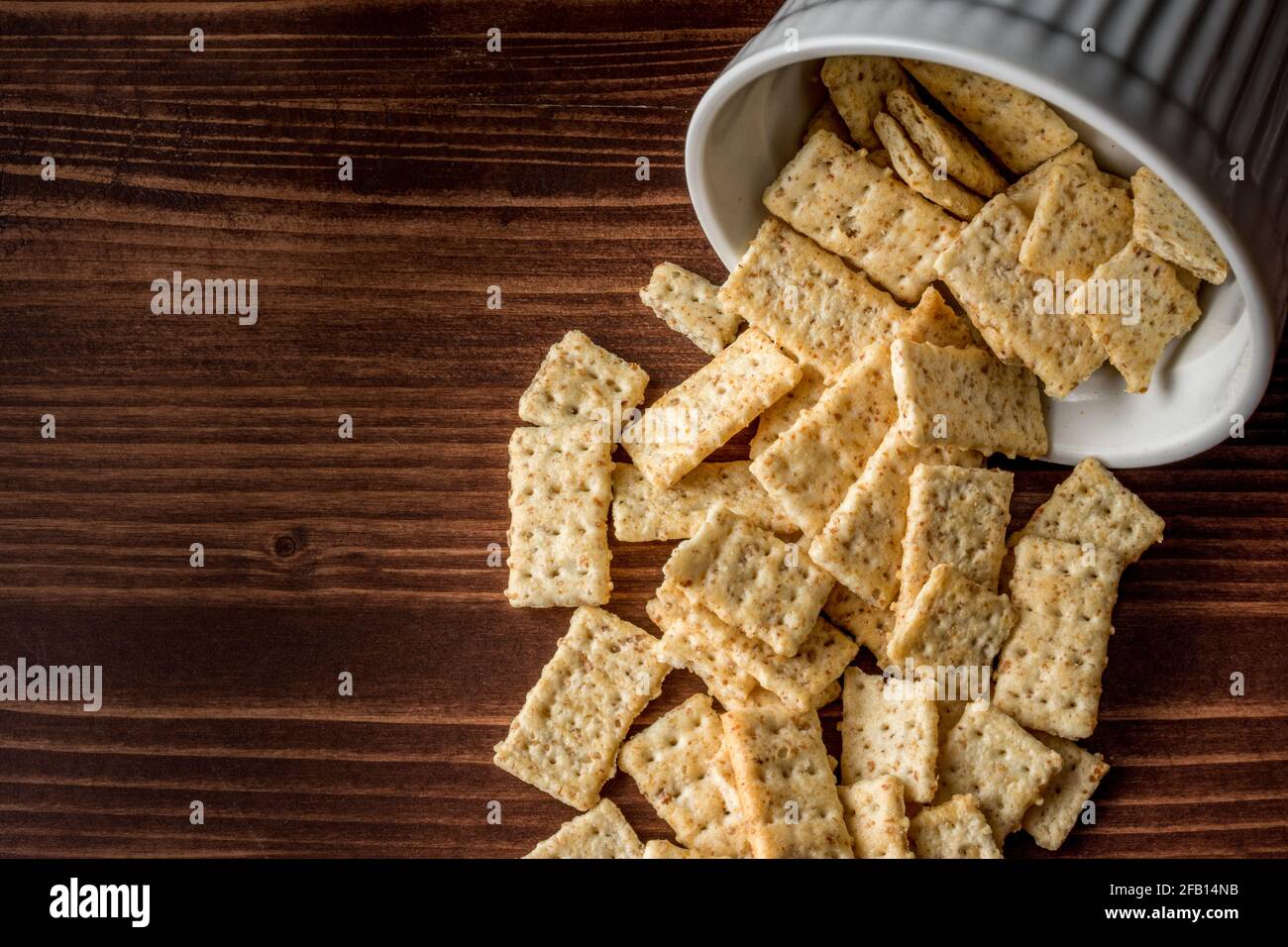 Rectangular crackers poured out on the wooden table from the bowl Stock ...