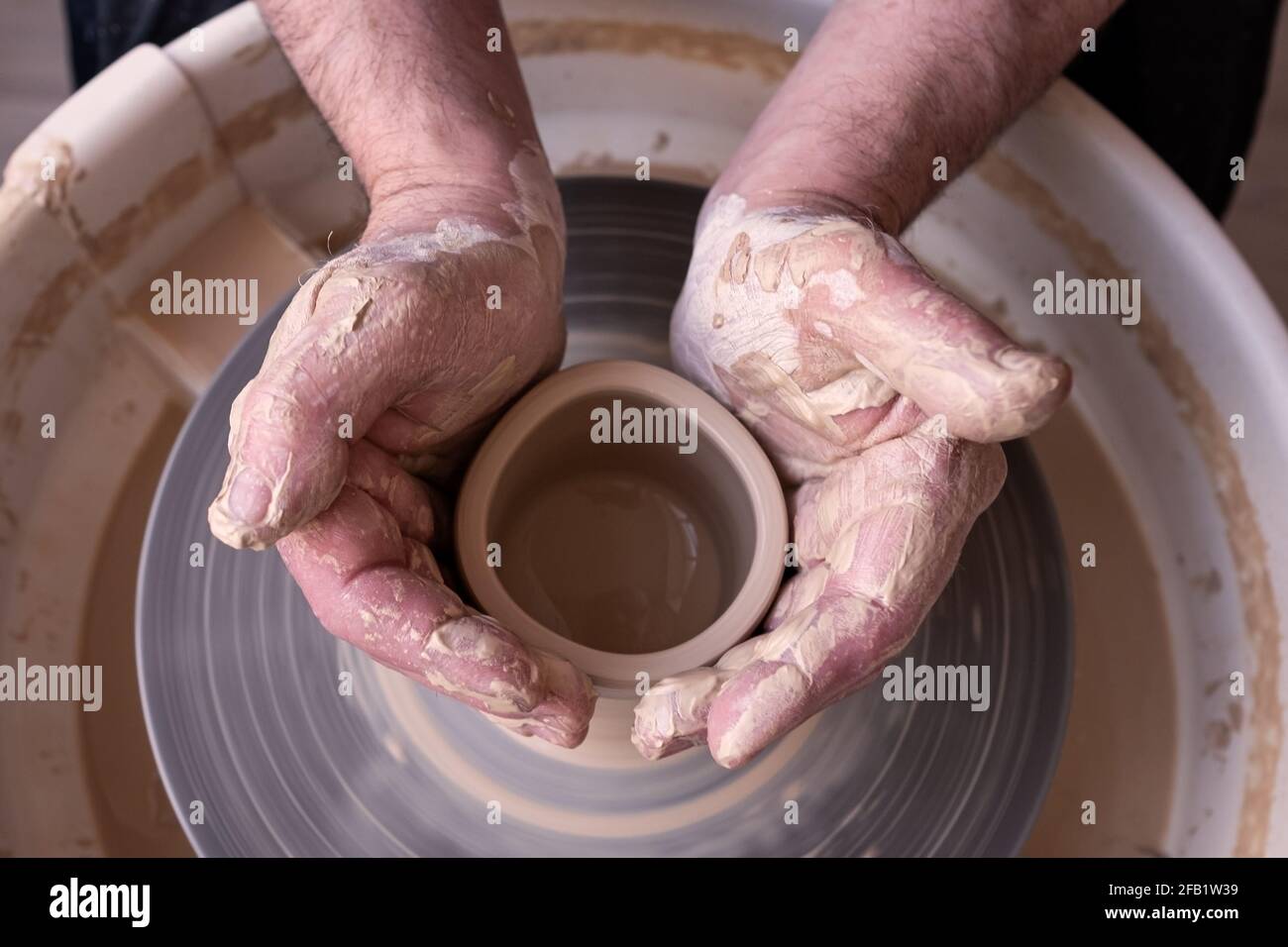 Potter wheel and hands of craftsman making a jug. Top view Stock Photo ...