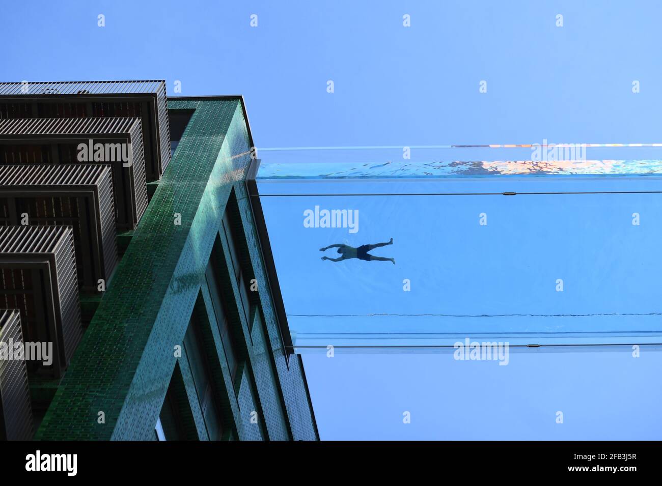 A man swims in the Sky Pool, a transparent swimming pool bridge across ...