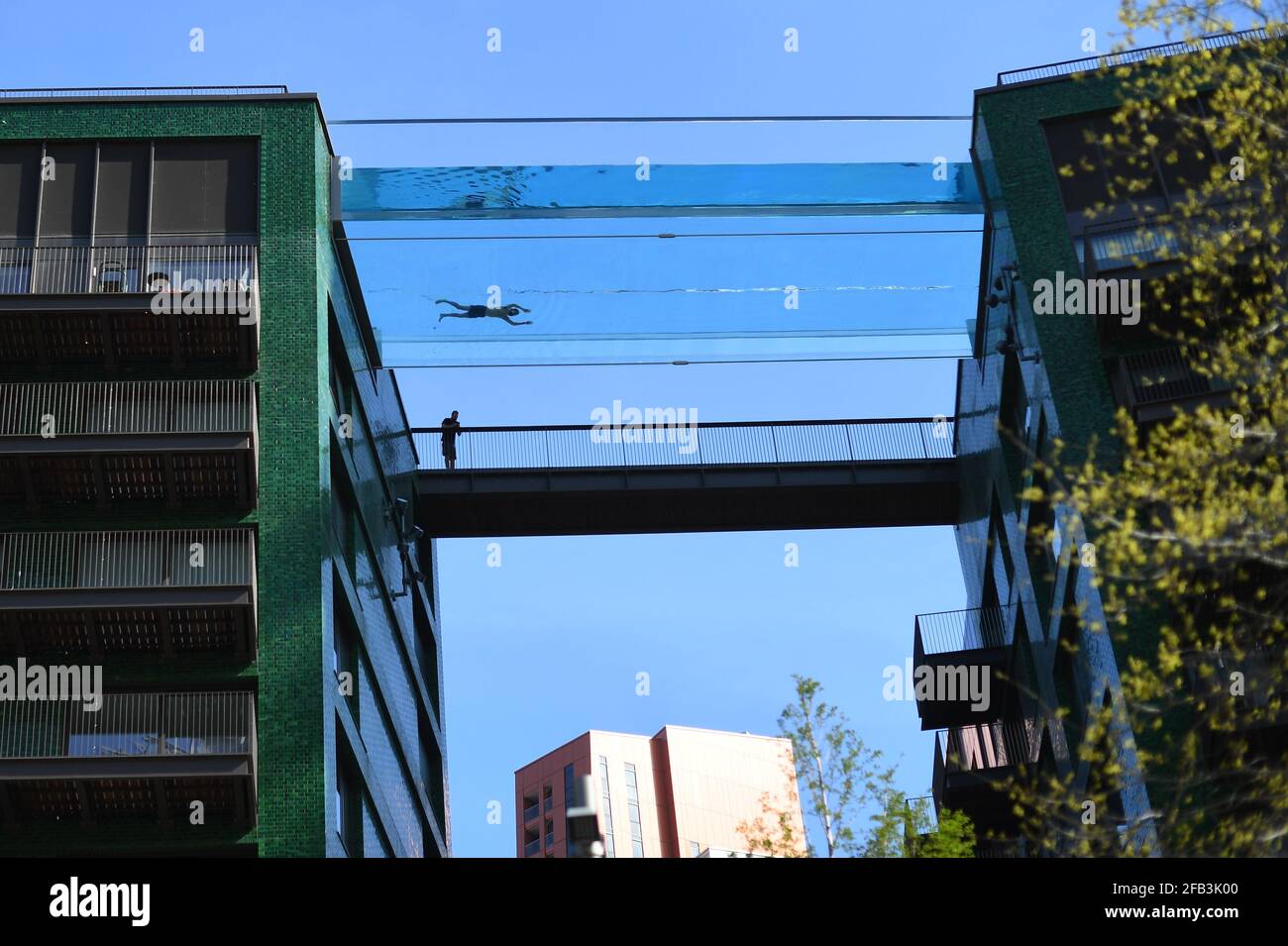 A man swims in the Sky Pool, a transparent swimming pool bridge across ...