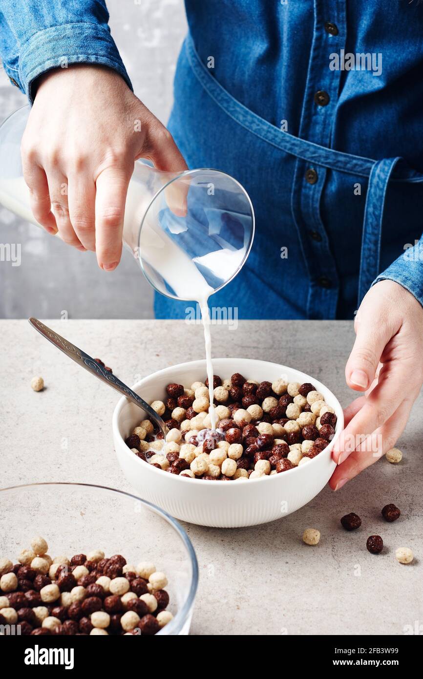 Female hands pour milk into a bowl of breakfast cereals Stock Photo - Alamy