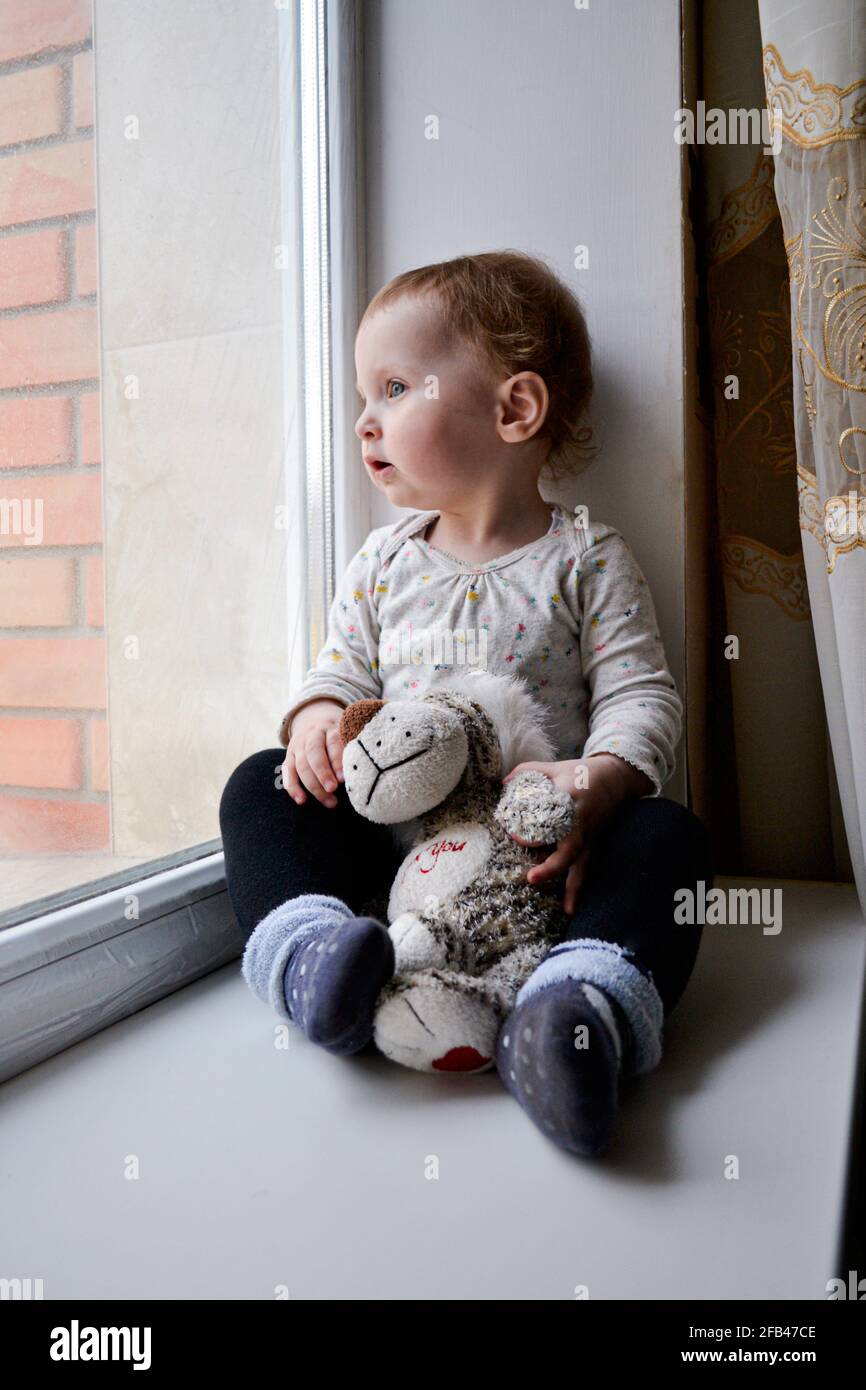 little girl sitting on windowsill and looking at the window Stock Photo ...