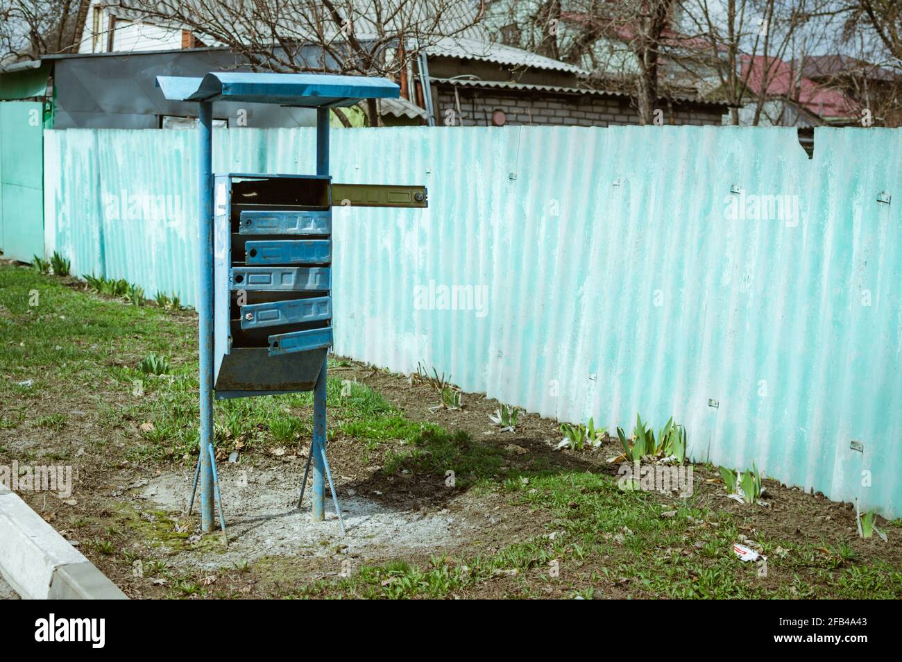 Old battered iron mailbox by fence Stock Photo - Alamy