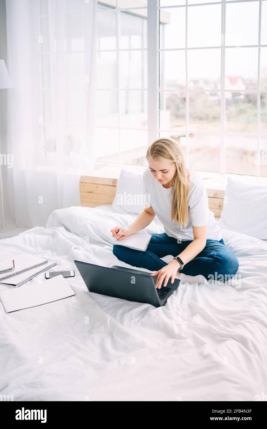 blonde girl working on laptop in bed Stock Photo - Alamy