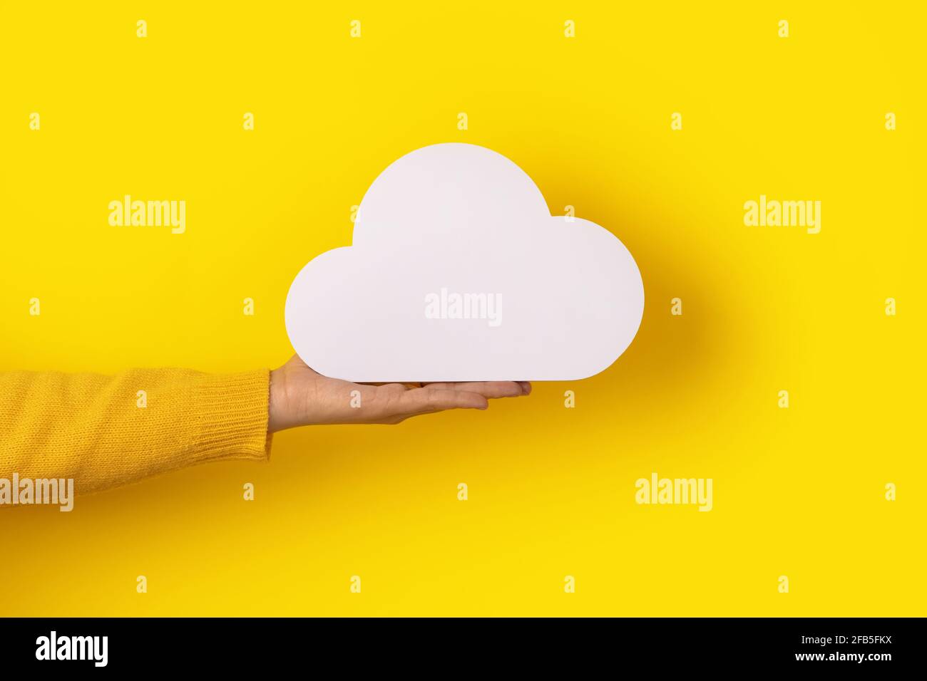 Cloud computing concept, hand holding cloud over yellow background ...