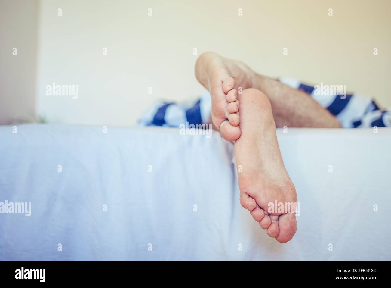 Closeup shot of a male sleeping in the bad, man feet Stock Photo - Alamy