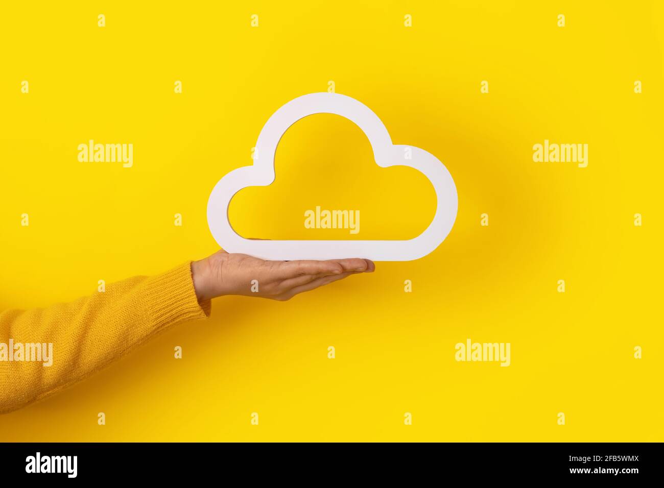 hand holding cloud icon over yellow background Stock Photo - Alamy
